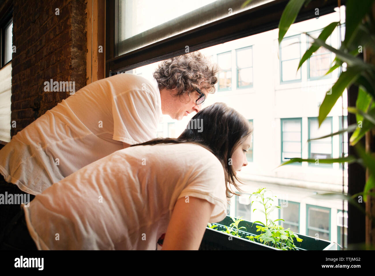 Side view of father and daughter looking through window Stock Photo - Alamy