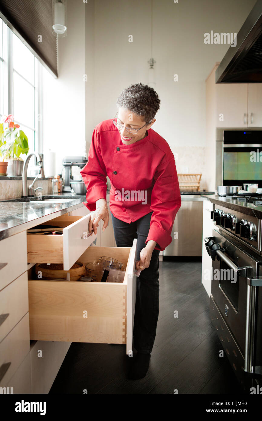 Woman opening drawers while working in kitchen Stock Photo - Alamy