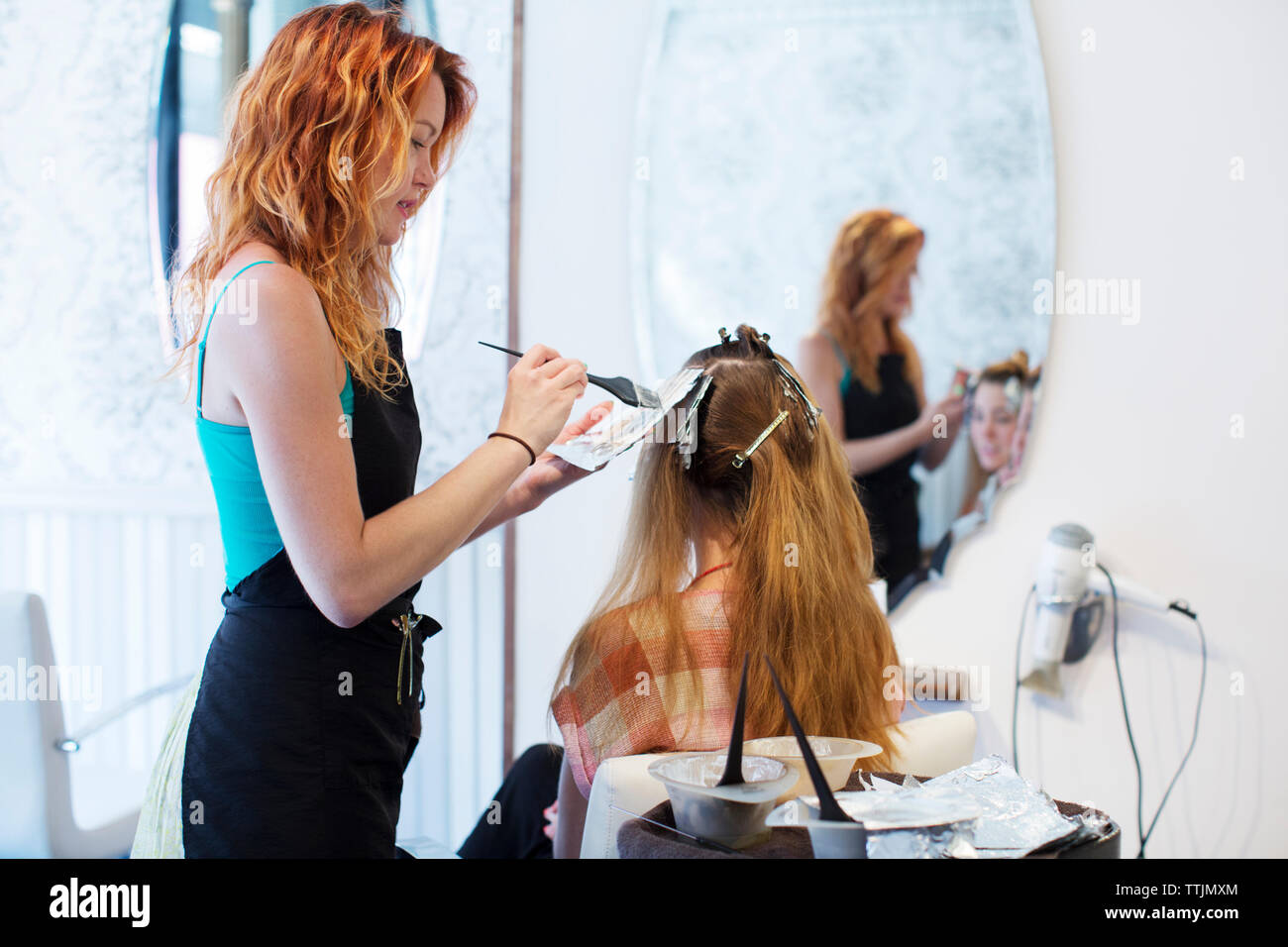 Side view of hairdresser applying dye to customer's hair Stock Photo ...