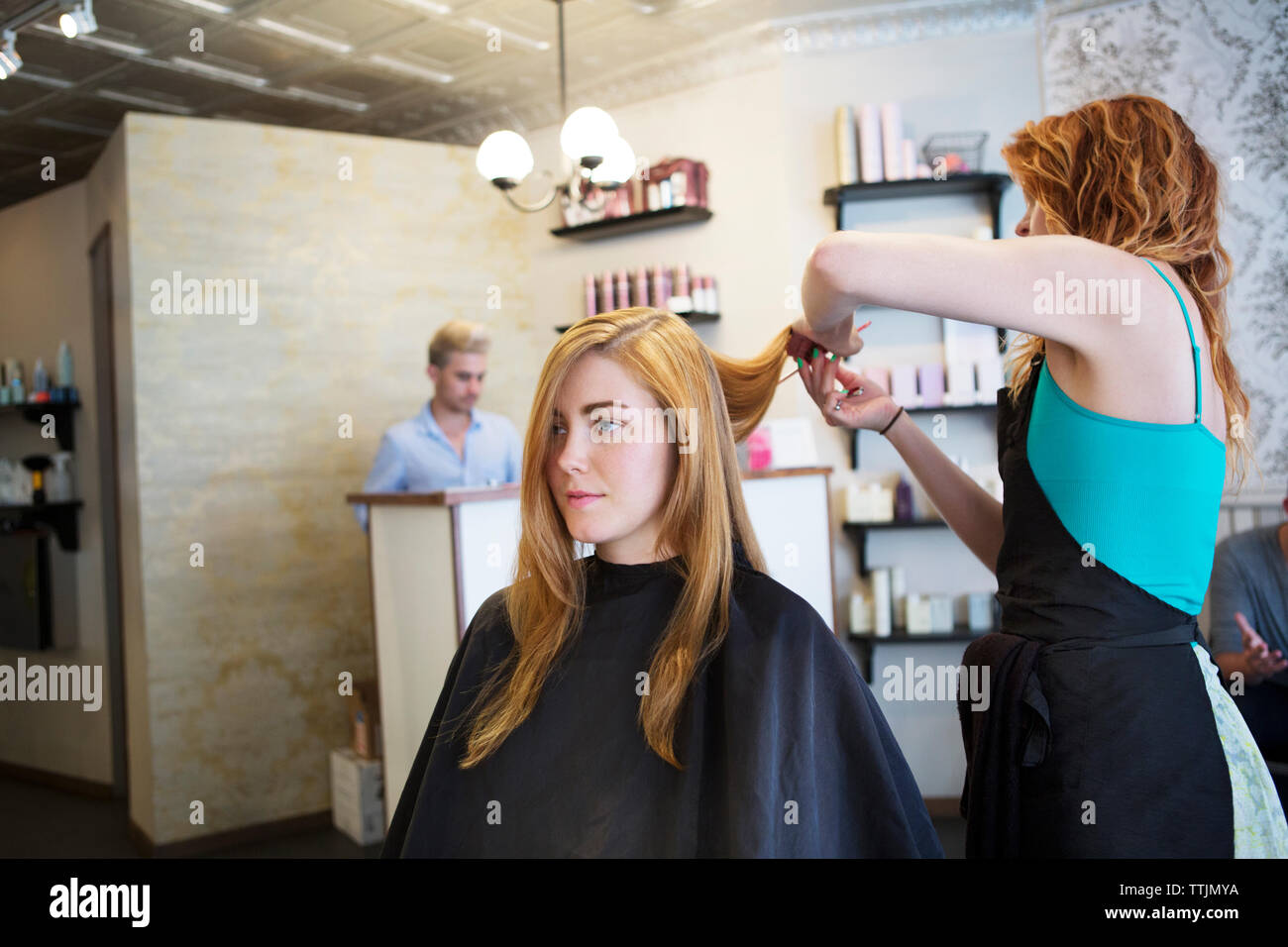Side view of hairstylist cutting woman's hair in salon Stock Photo - Alamy