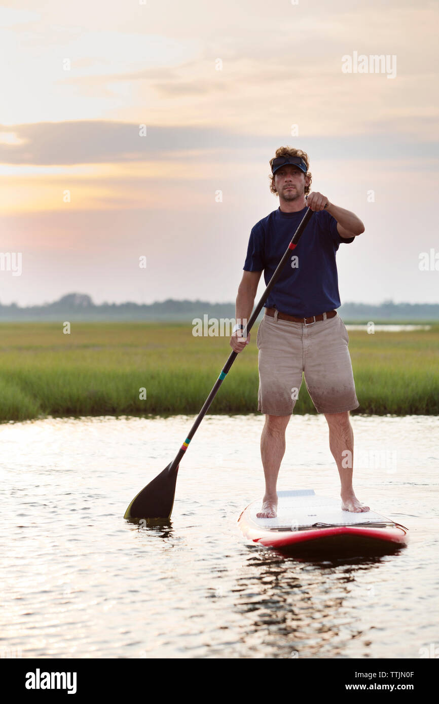 Man paddle boarding in lake during sunset Stock Photo - Alamy
