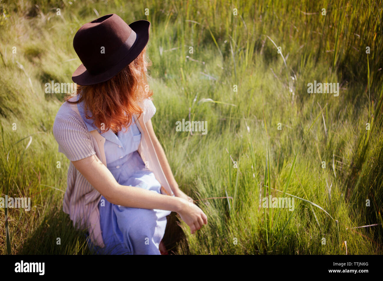 High angle view of woman crouching on grassy field Stock Photo - Alamy