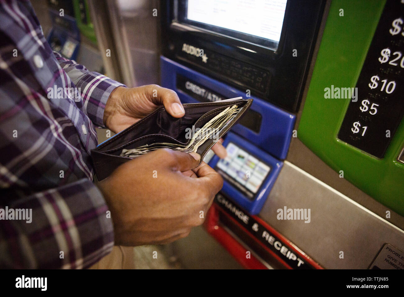 High angle view of man holding wallet while standing against ATM ...