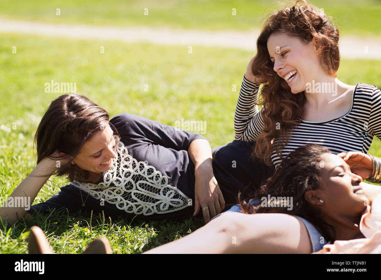 Smiling friends relaxing at park Stock Photo - Alamy