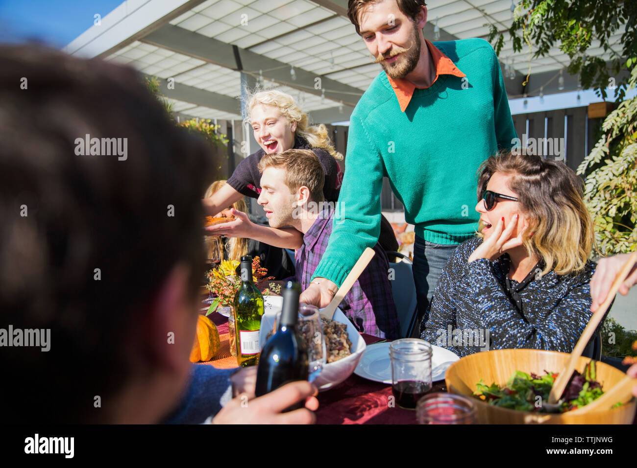 Man serving food to friends during garden party Stock Photo - Alamy