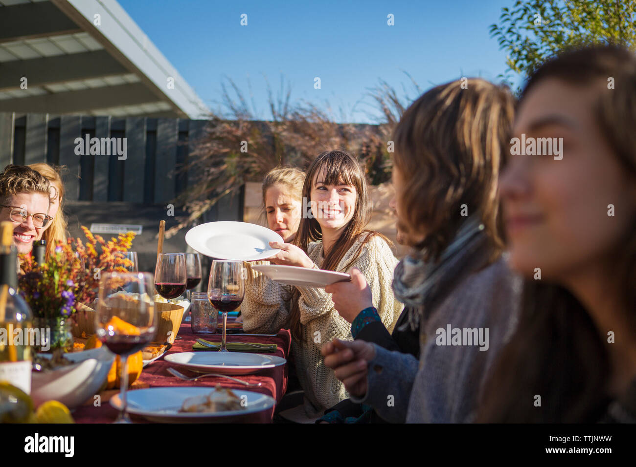 Happy woman passing plates to friends during garden party Stock Photo ...