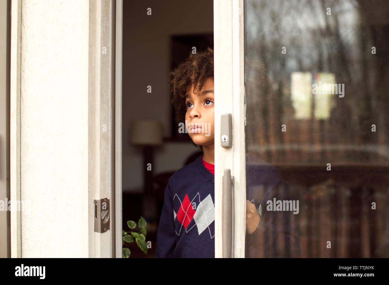 Thoughtful boy looking through window at home Stock Photo - Alamy