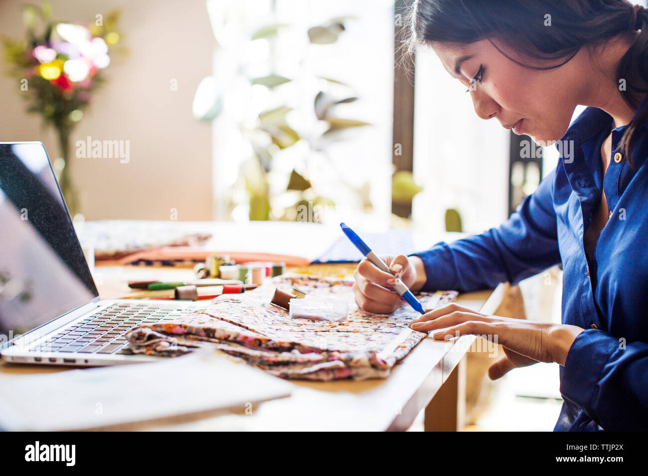 Side view of fashion designer marking on fabric in office Stock Photo ...