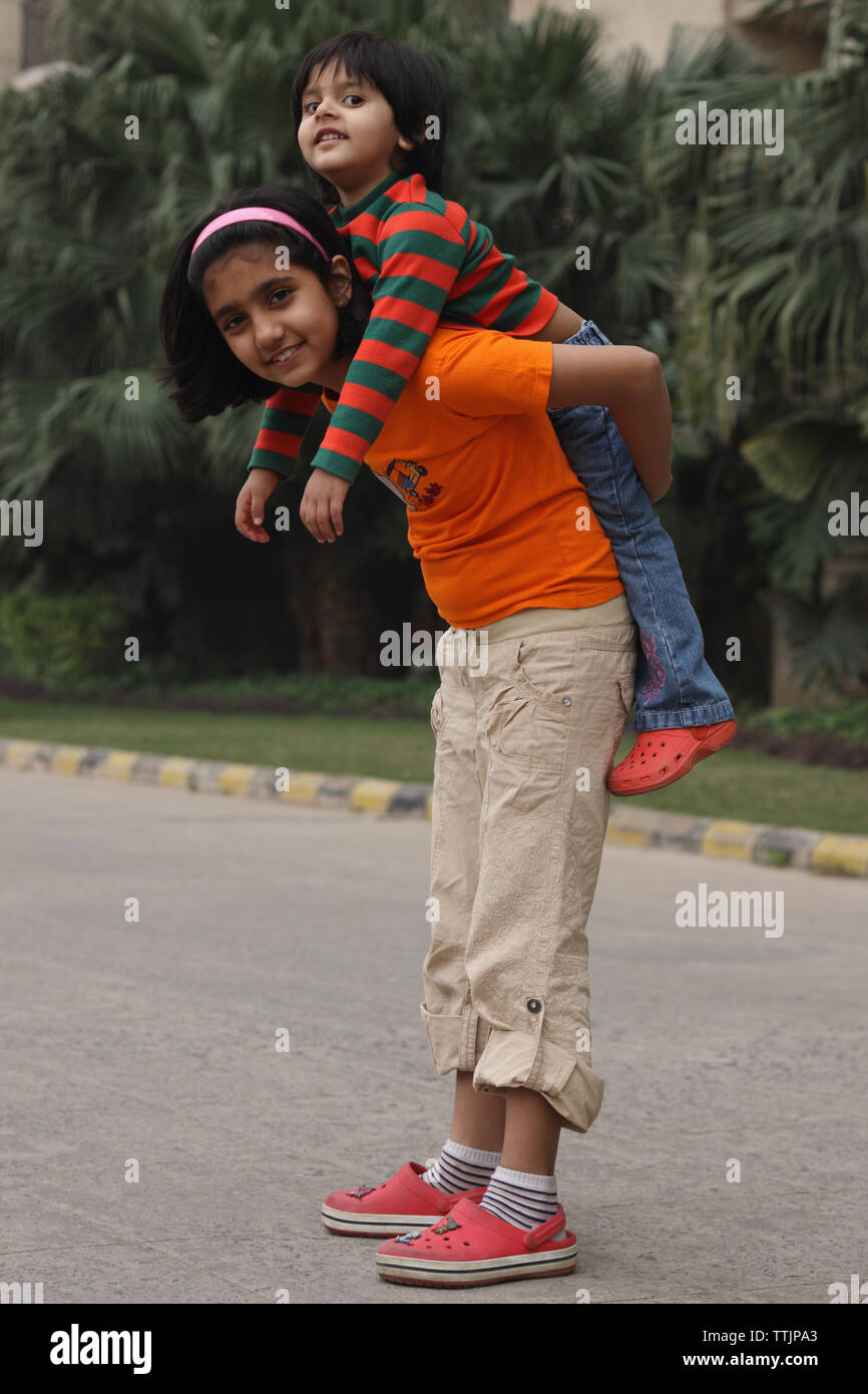 Girl riding piggyback on her friend Stock Photo - Alamy