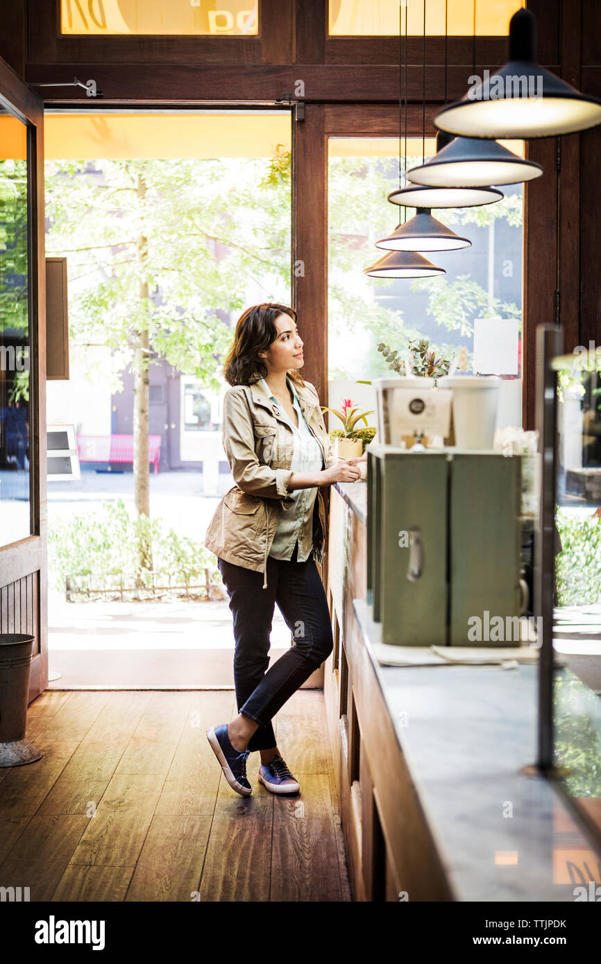 Thoughtful woman standing at checkout counter in cafe Stock Photo - Alamy