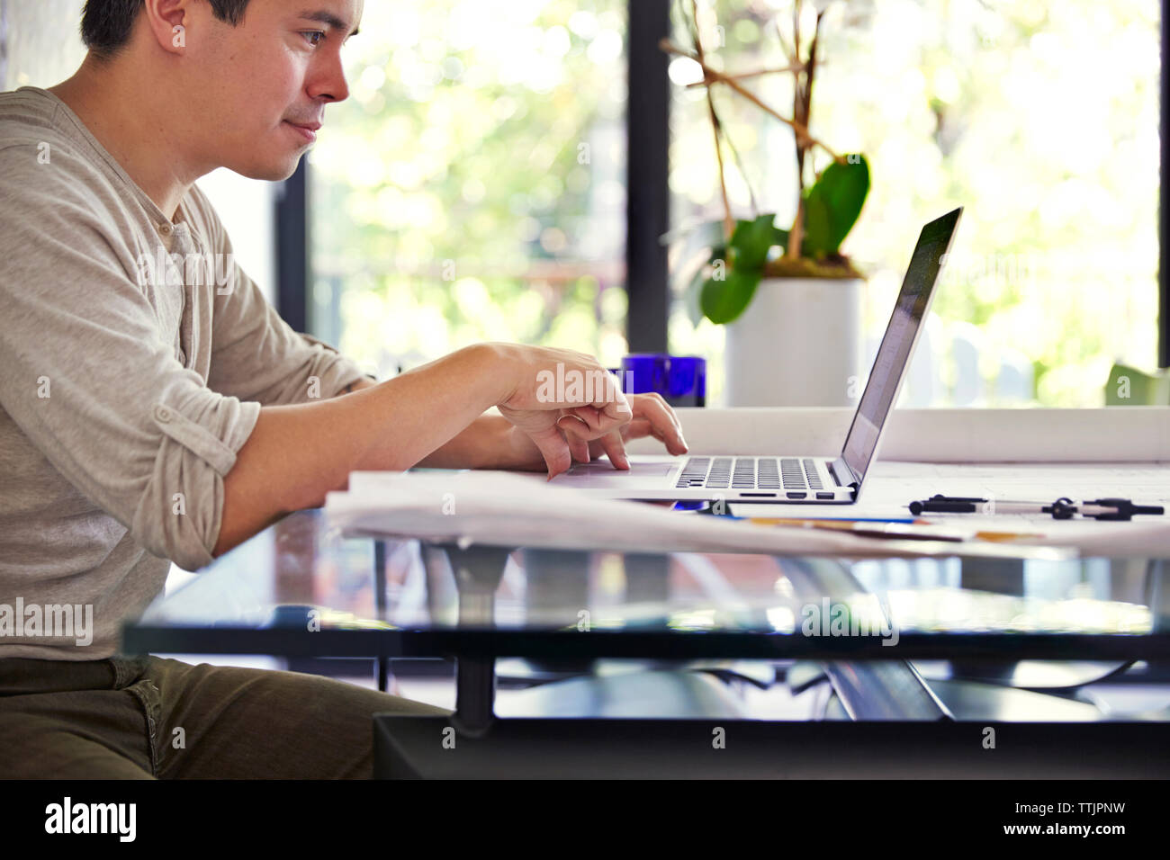 Side view of serious man using laptop computer at table in office Stock ...