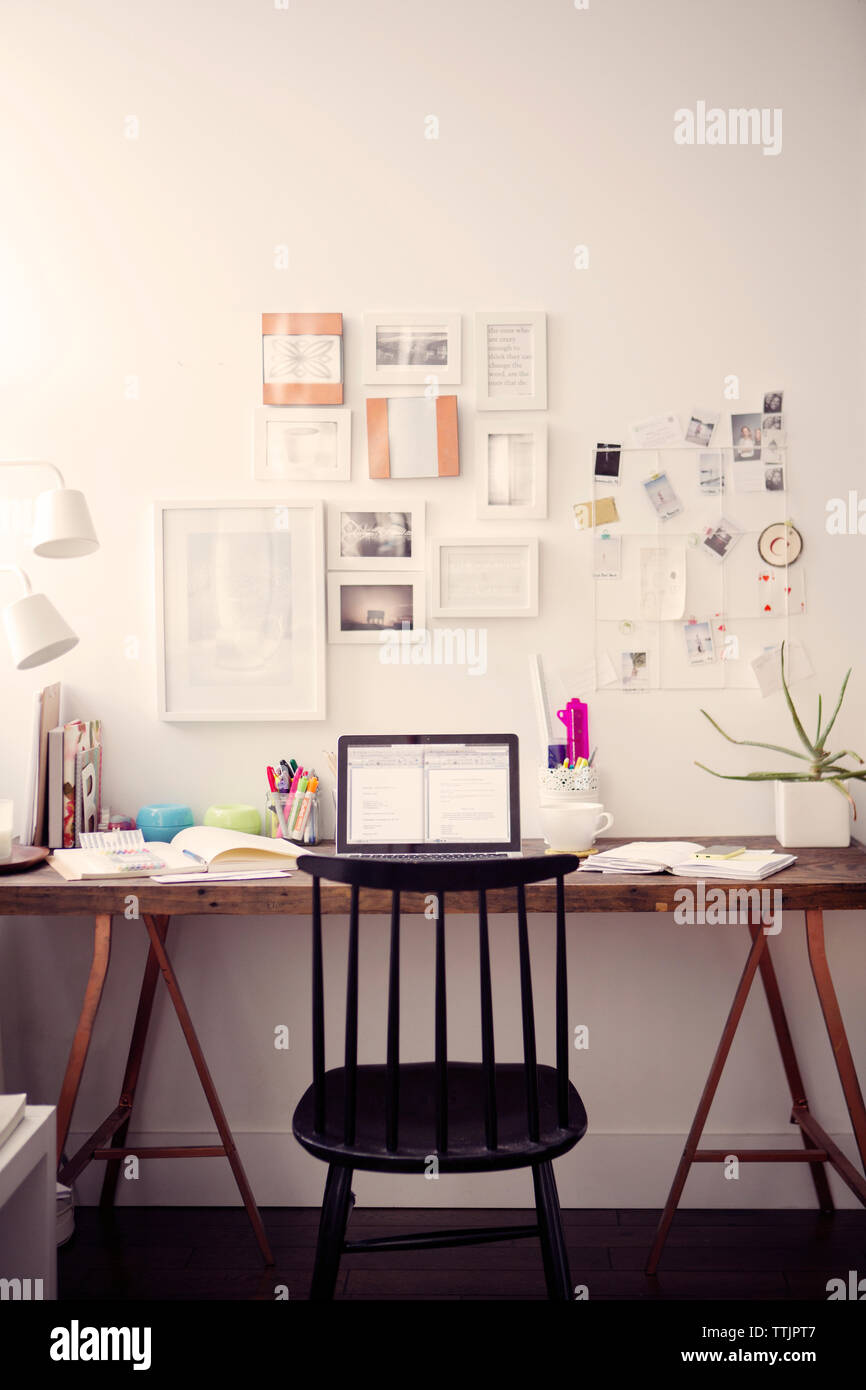 Chair and table with laptop computer against papers on wall at home ...
