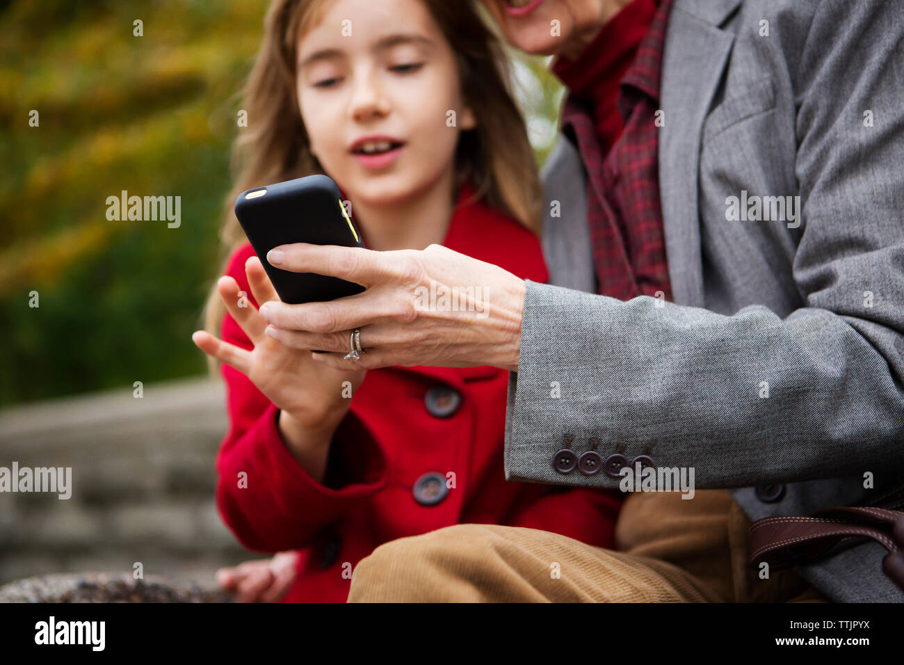 Family using mobile phone while sitting in park Stock Photo - Alamy
