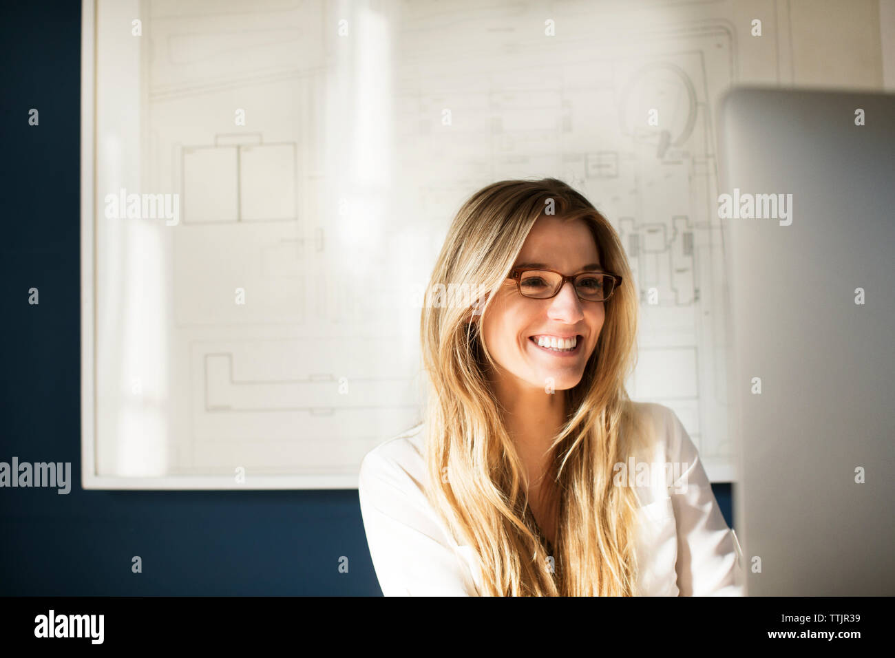 Happy woman using desktop computer while working in office Stock Photo ...