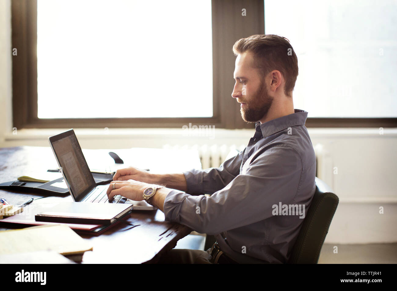 Side view of businessman using laptop computer while working in office ...