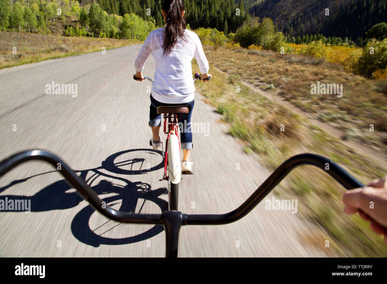 Rear view of woman riding bicycle on road Stock Photo - Alamy