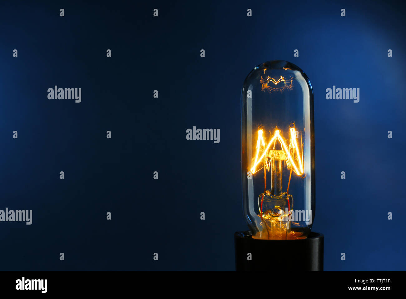 Illuminated light bulb on dark blue background Stock Photo - Alamy