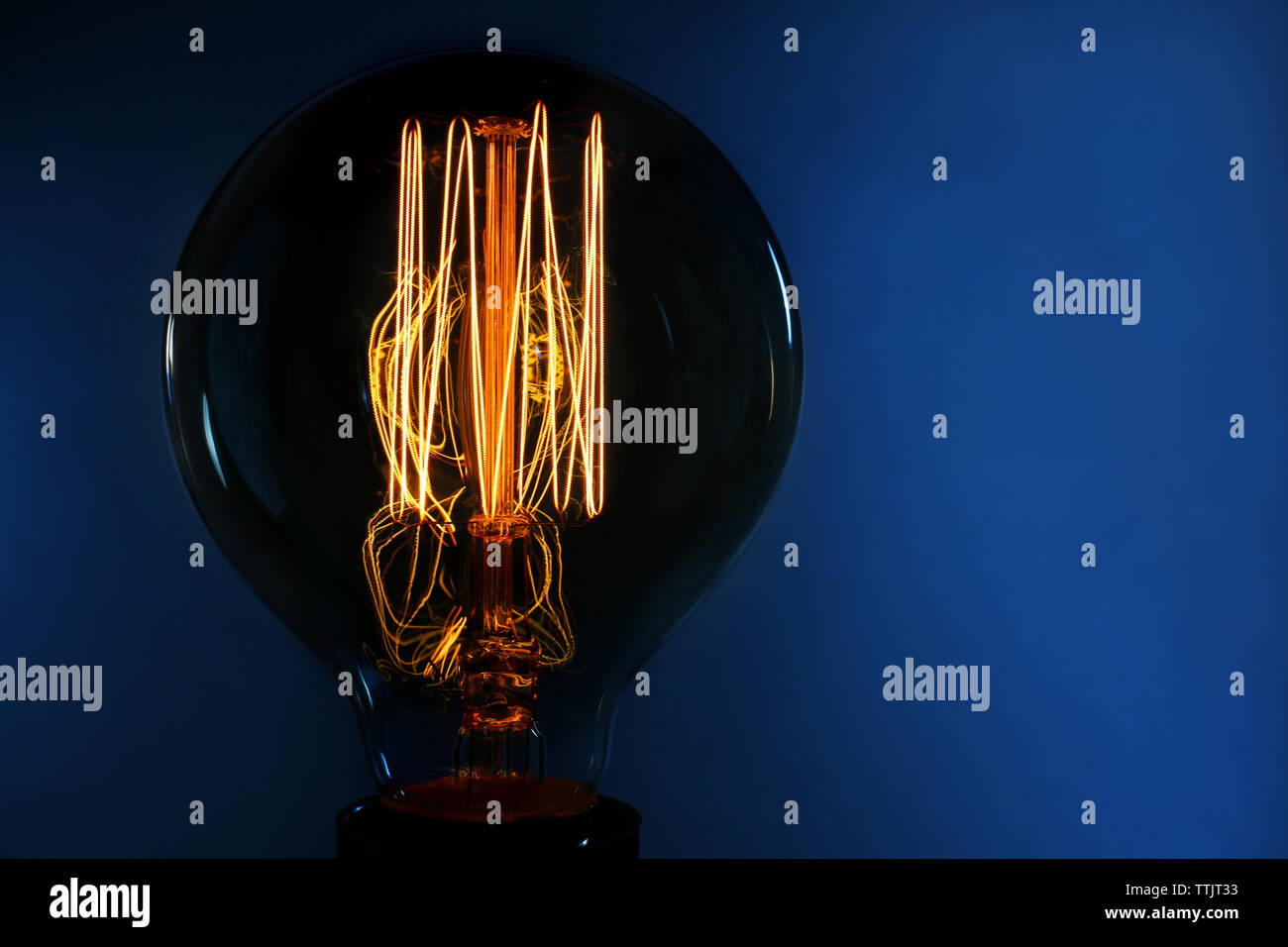 Illuminated light bulb on dark blue background Stock Photo - Alamy