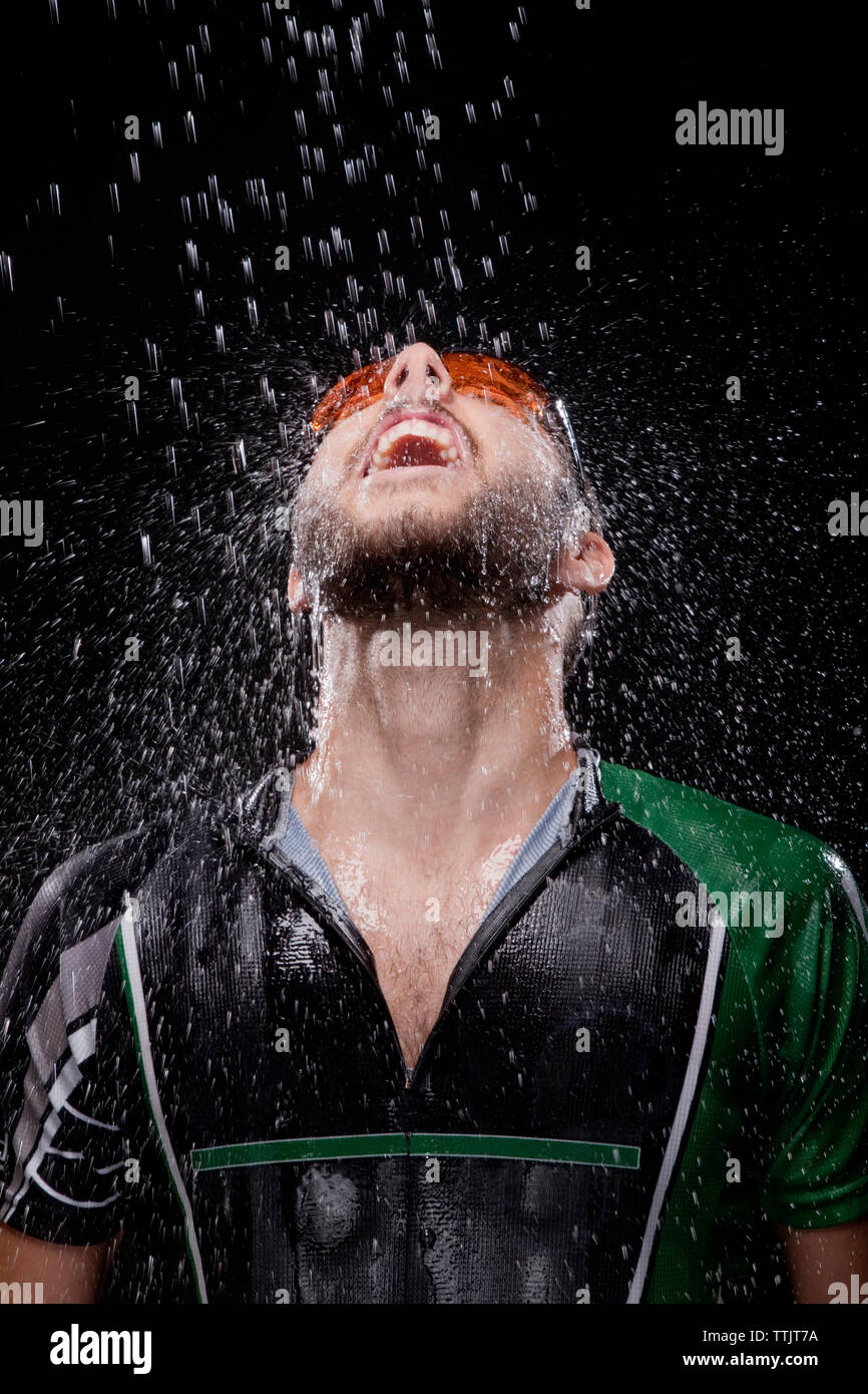 Man taking shower while standing against black background Stock Photo ...