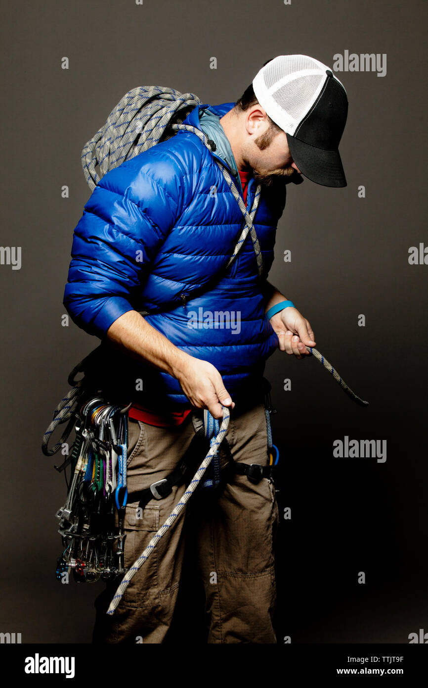 Hiker wearing safety harness tying rope around waist while standing ...