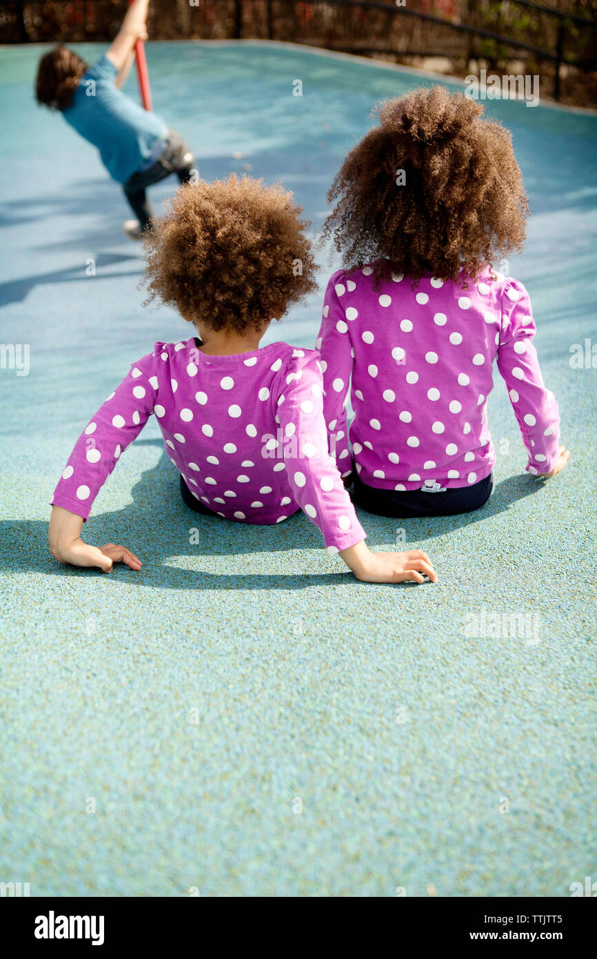Rear view of children sitting in playground Stock Photo - Alamy