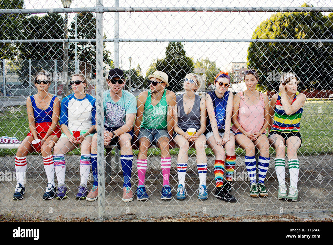 Spectators sitting behind chainlink fence on field Stock Photo - Alamy