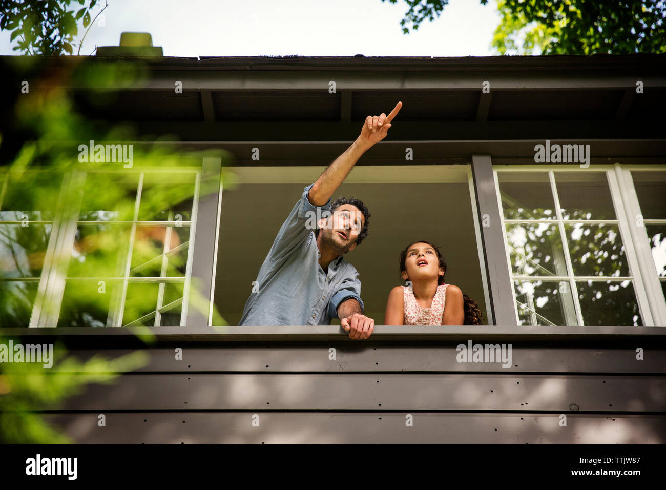 Low angle view of father showing daughter while standing at house ...