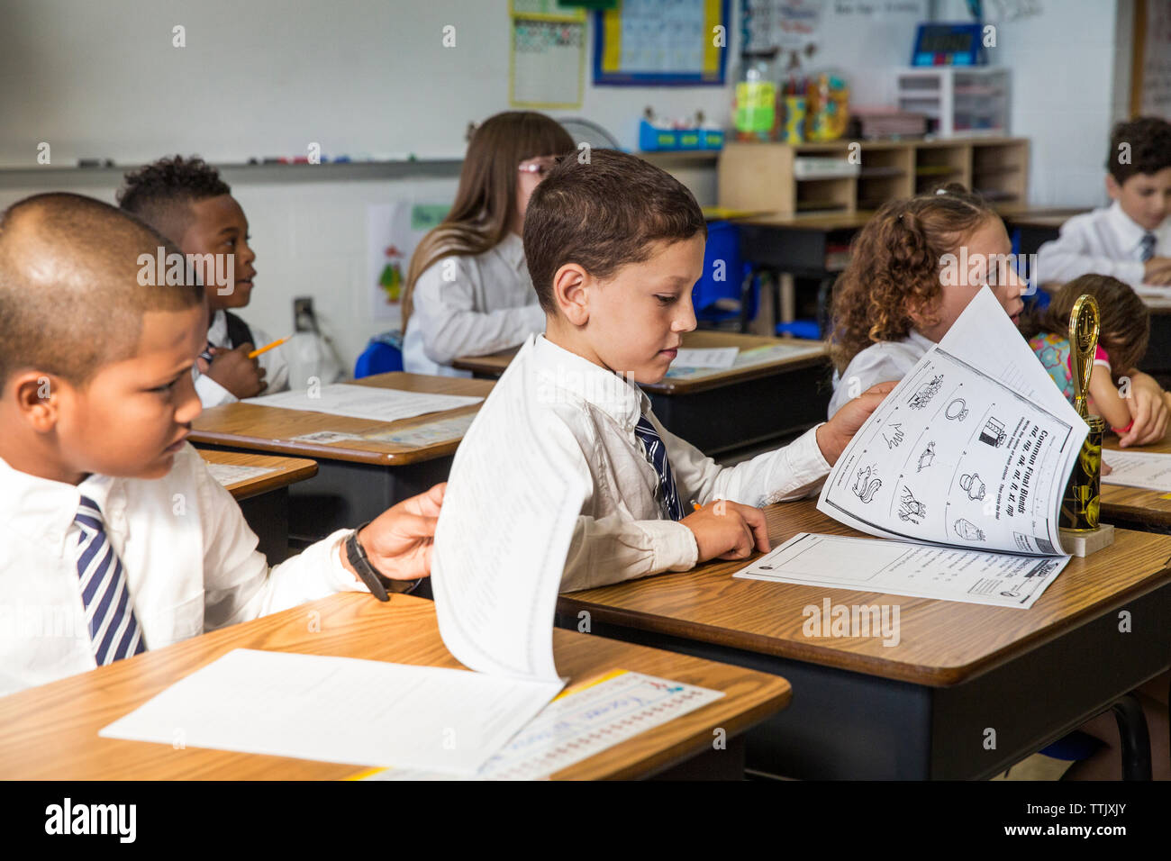 Students looking at books during lesson in classroom Stock Photo - Alamy
