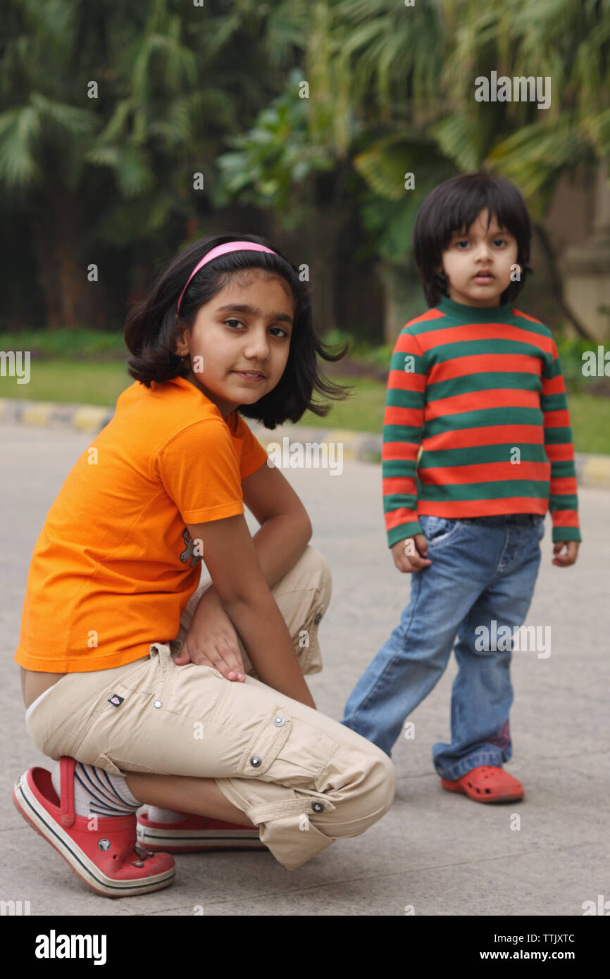 Indian girl crouching beside her sister on walkway Stock Photo - Alamy