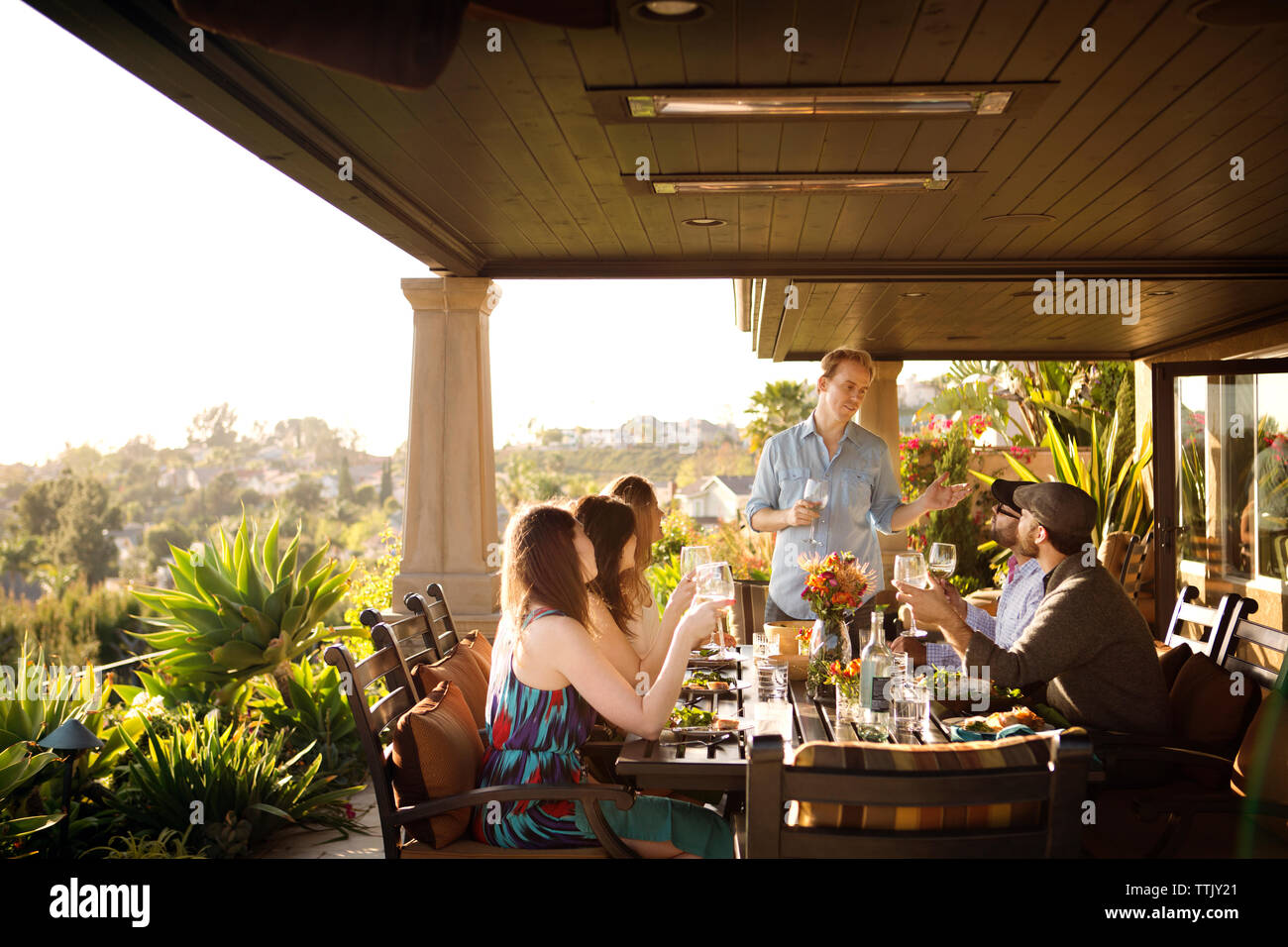 Friends talking while having drink at table at porch Stock Photo - Alamy