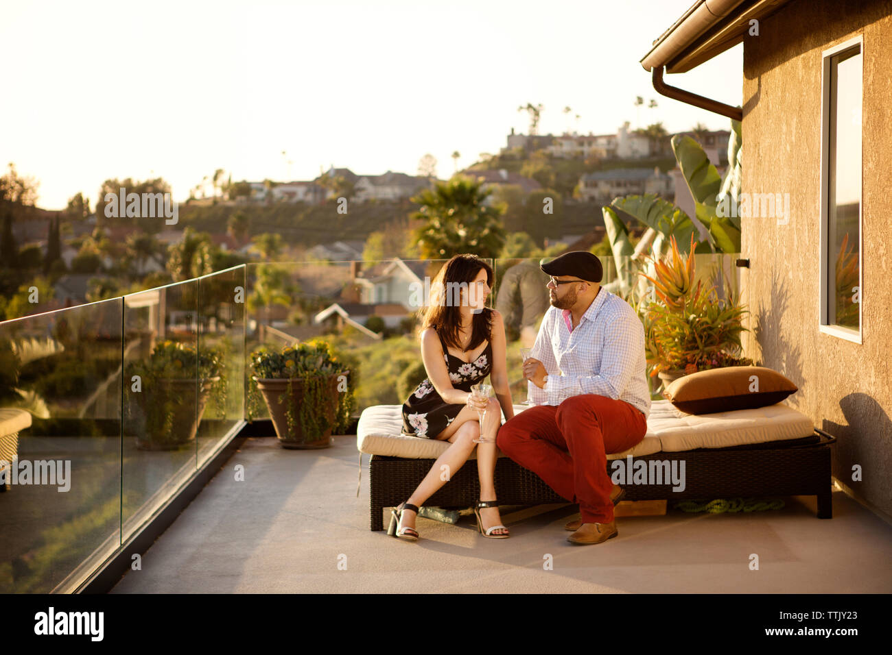Friends talking while sitting on seat in balcony Stock Photo - Alamy