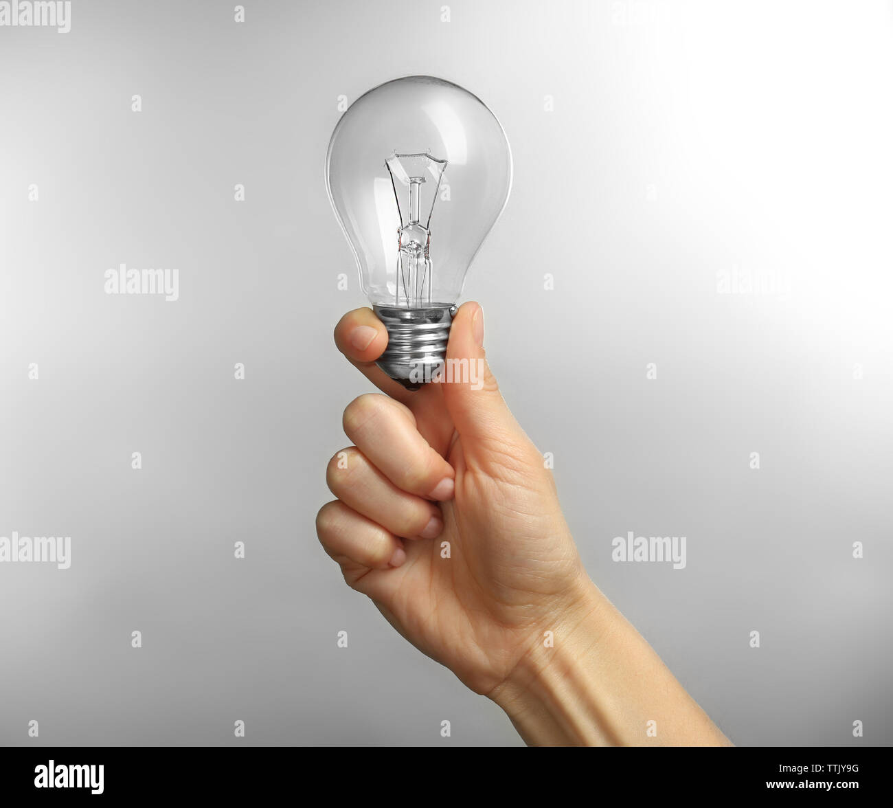 Woman hand holding bulb on grey background Stock Photo - Alamy