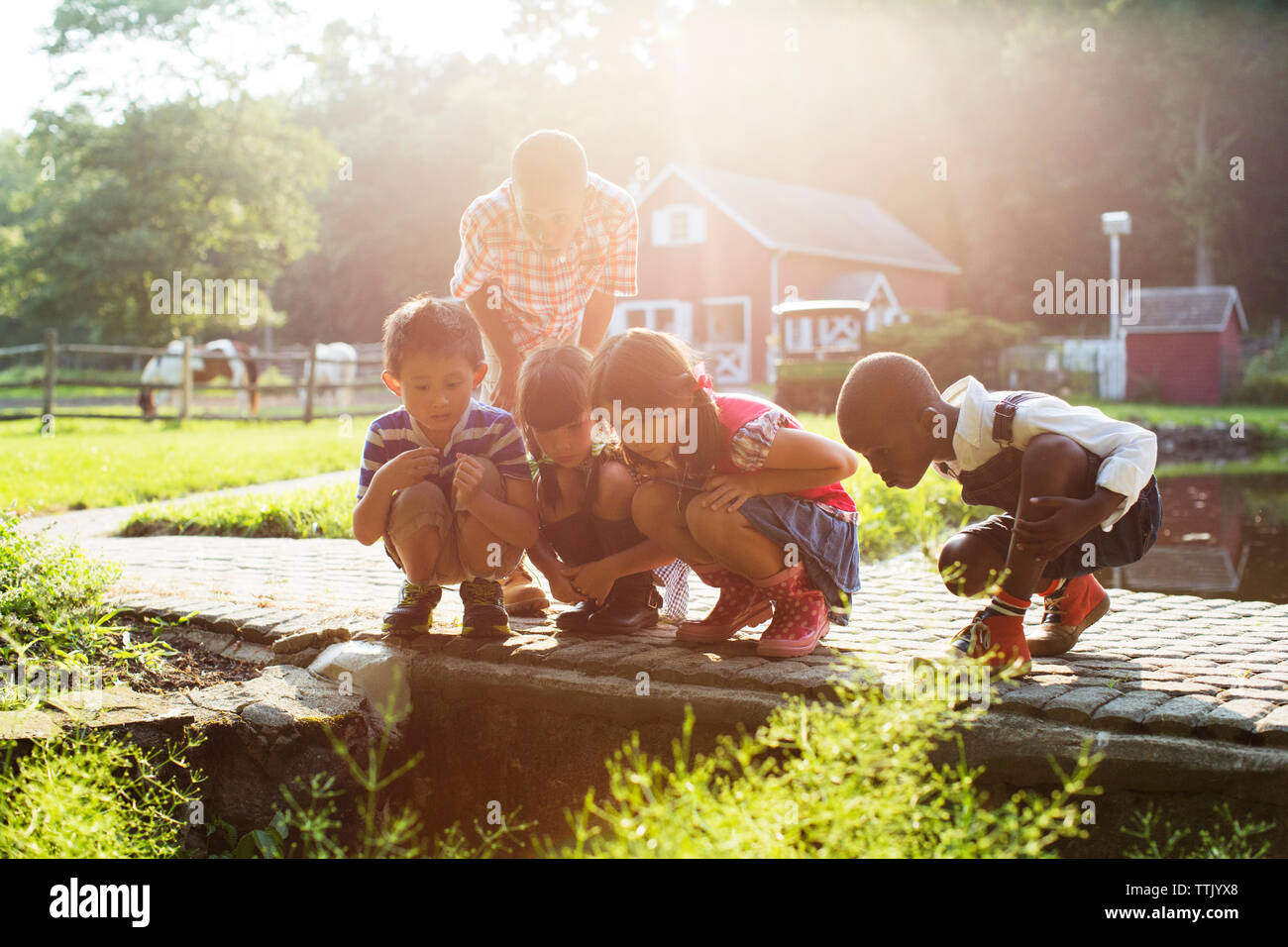 Children looking down while crouching on footbridge Stock Photo - Alamy