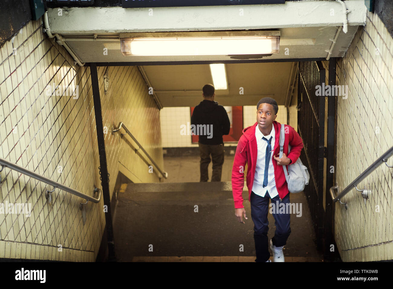Full length of student wearing school uniform walking upstairs from ...