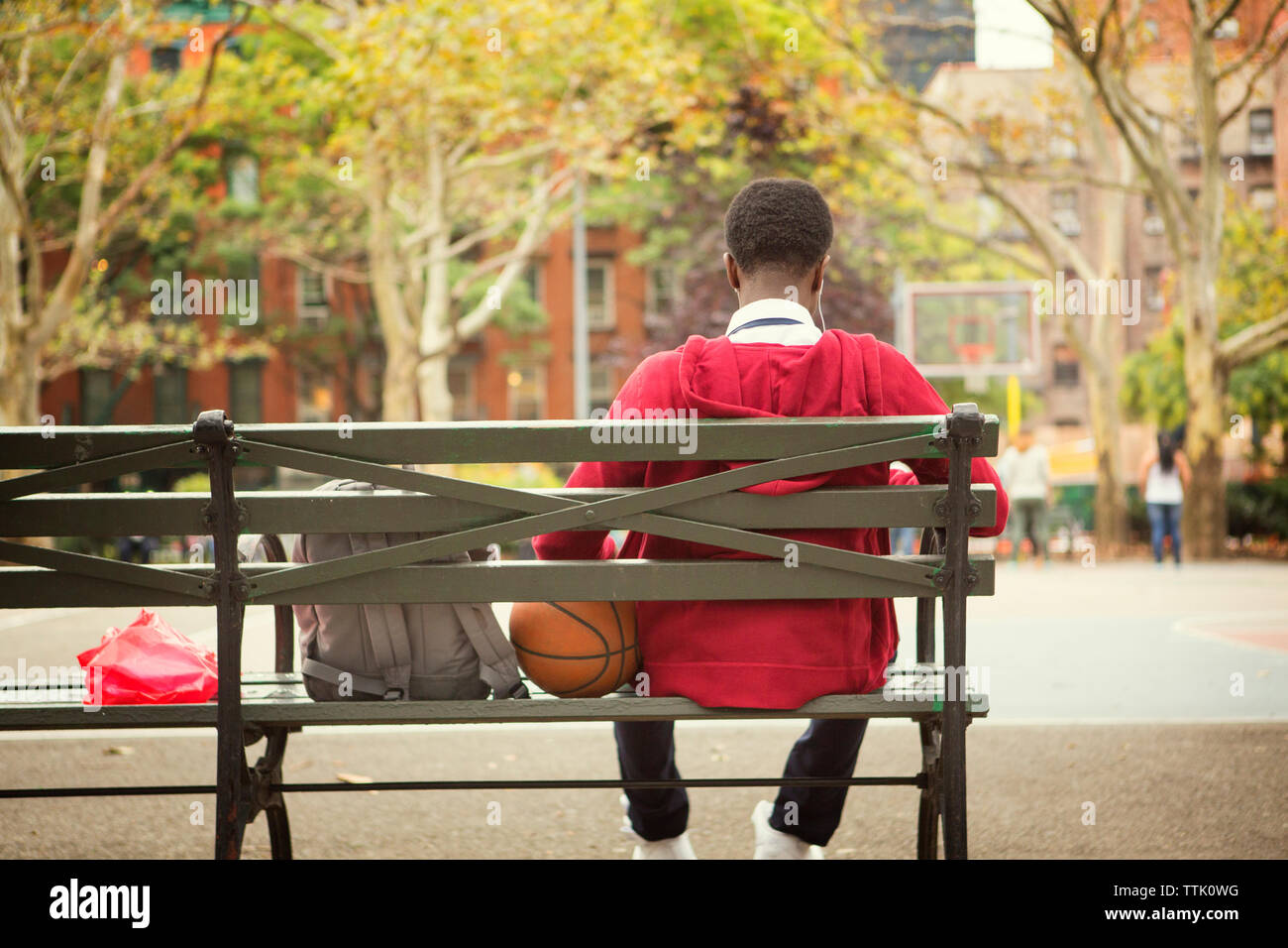 Rear view of student sitting on bench at basketball court Stock Photo ...