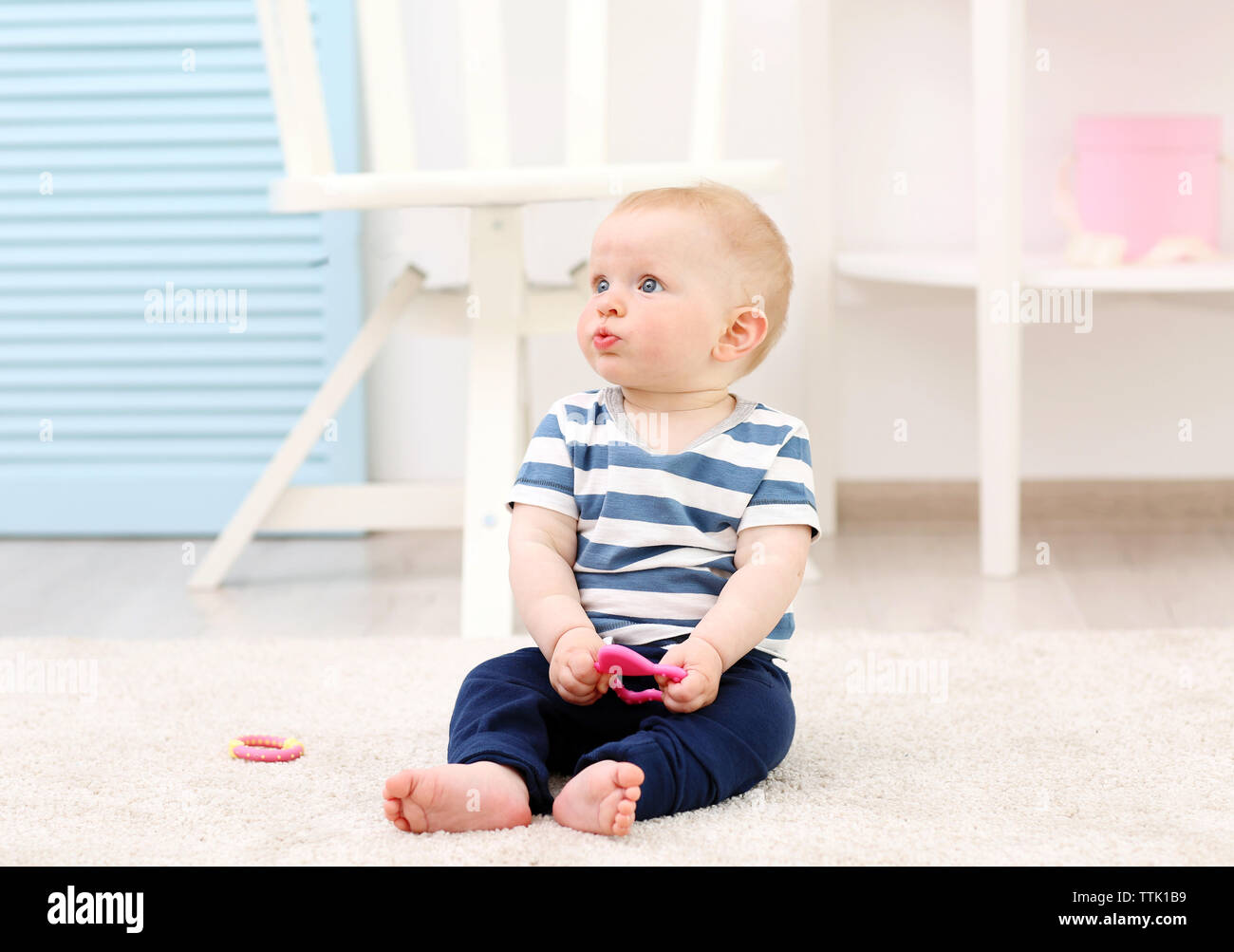 Adorable baby sitting on a carpet Stock Photo - Alamy