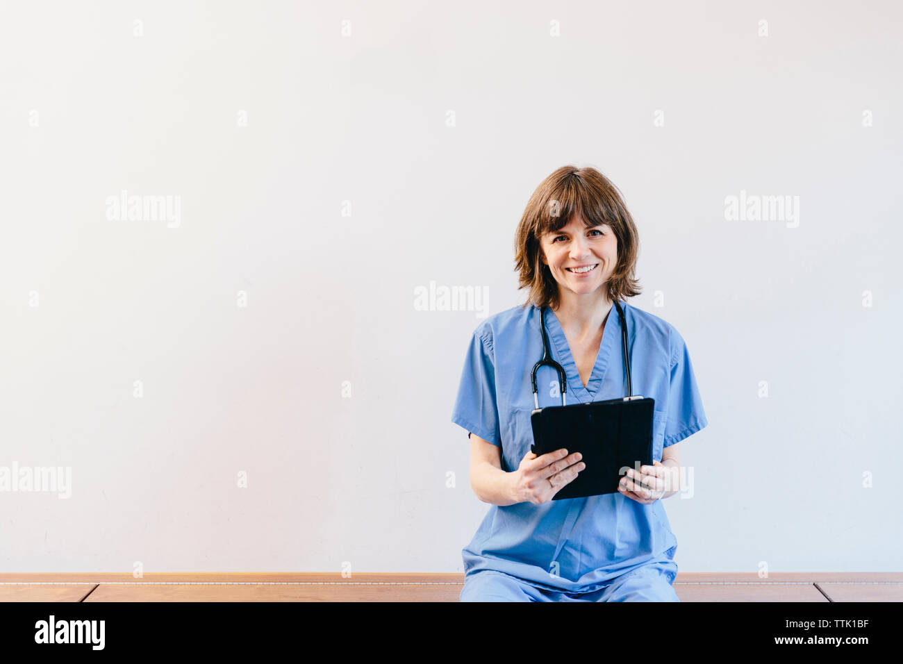Portrait of female doctor holding tablet computer while sitting on ...