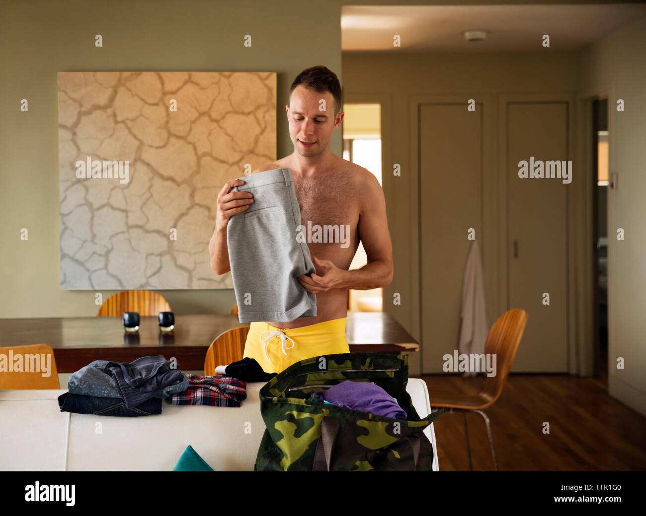 Shirtless man packing bag while standing in resort Stock Photo - Alamy