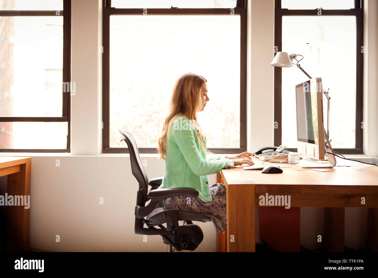 Side view of businesswoman using computer at office desk Stock Photo ...