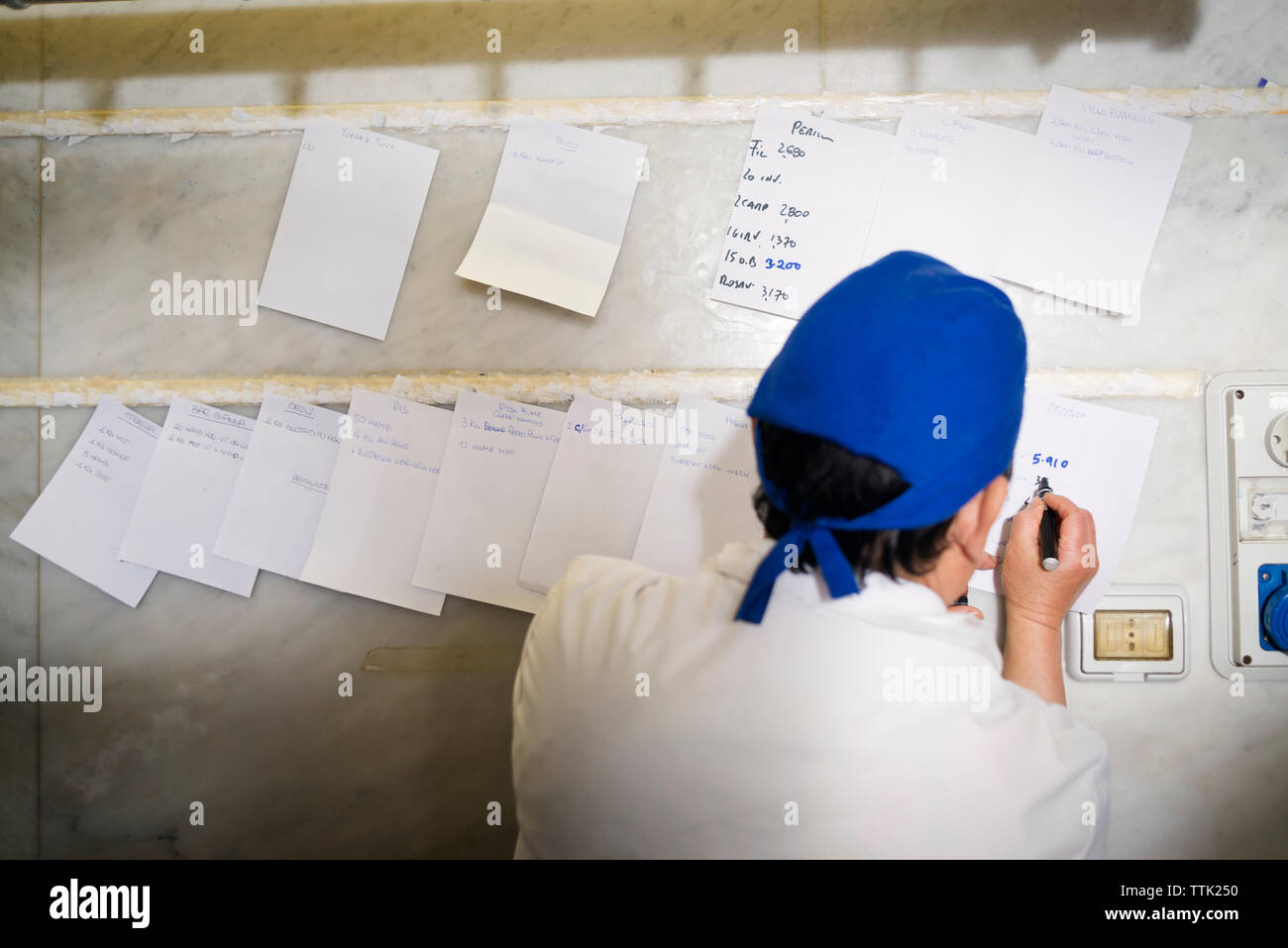 Rear view of butcher writing orders on notes at shop Stock Photo - Alamy