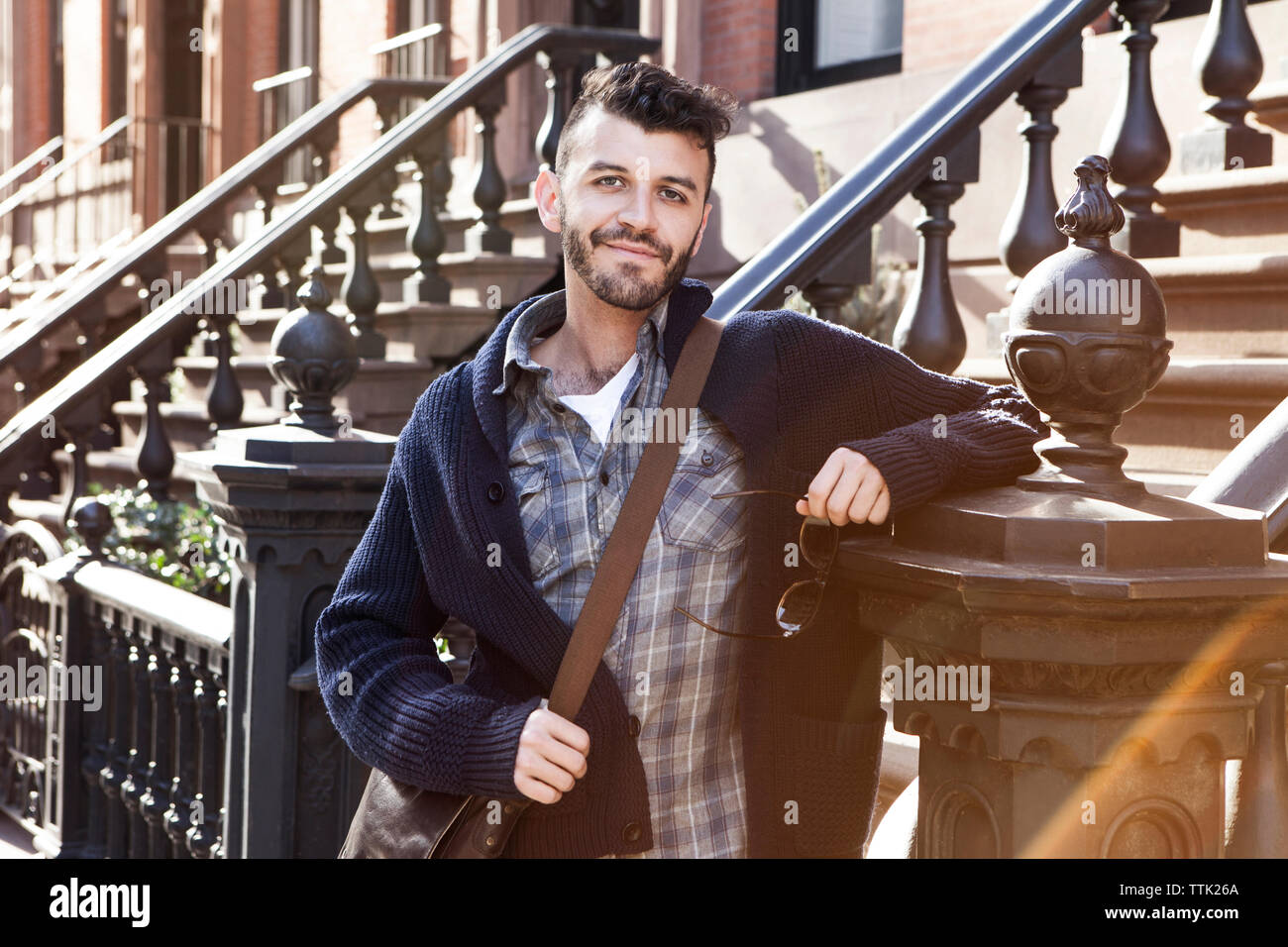 Portrait of man leaning on railing by building at city Stock Photo - Alamy