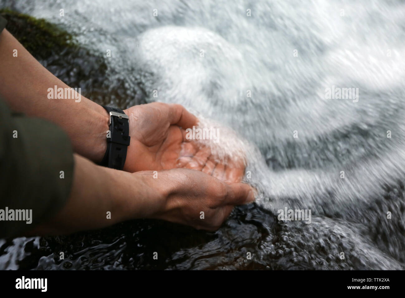 Male tourist drinking water from river Stock Photo - Alamy