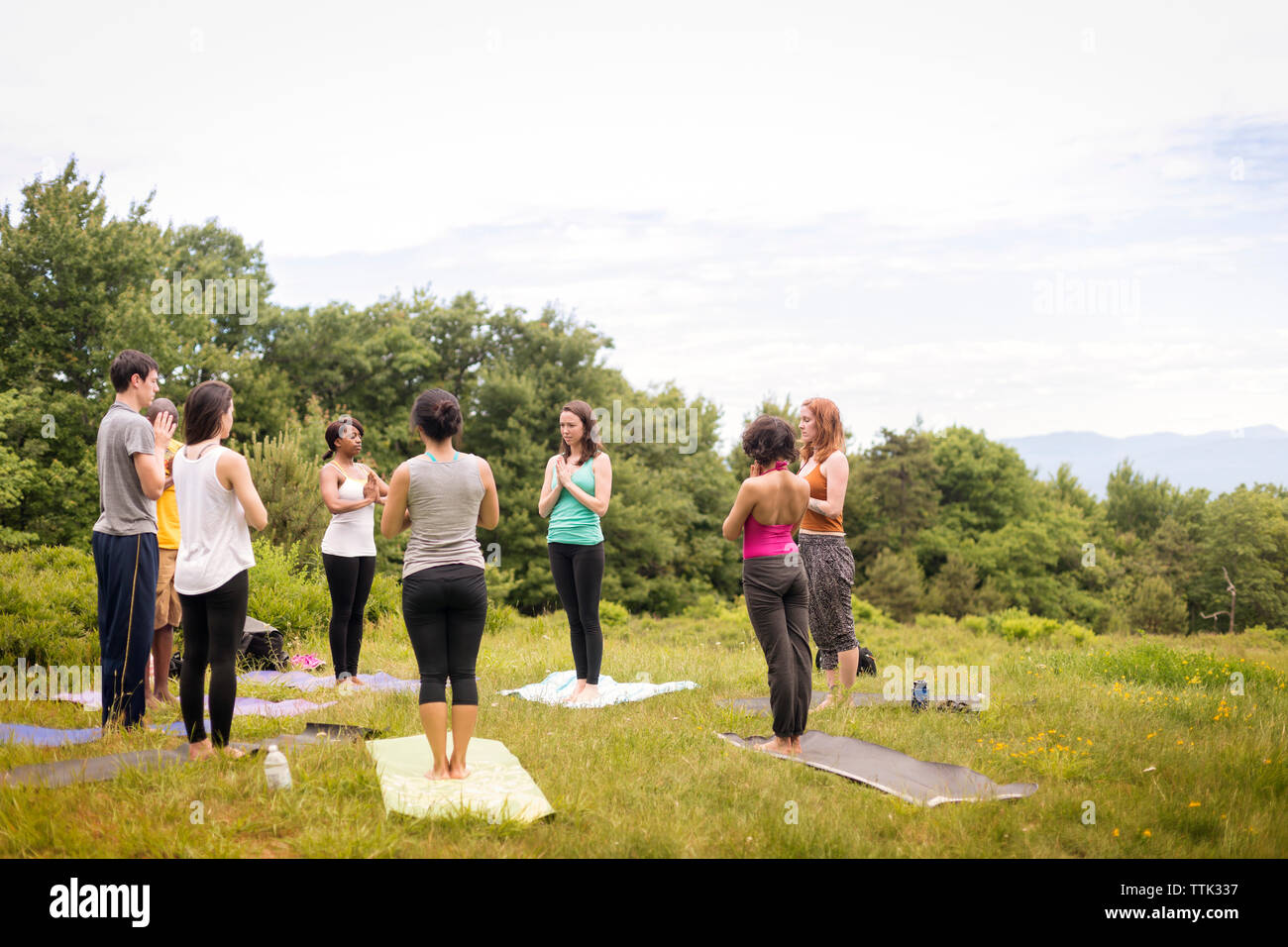 Friends standing in prayer position while exercising on field Stock ...