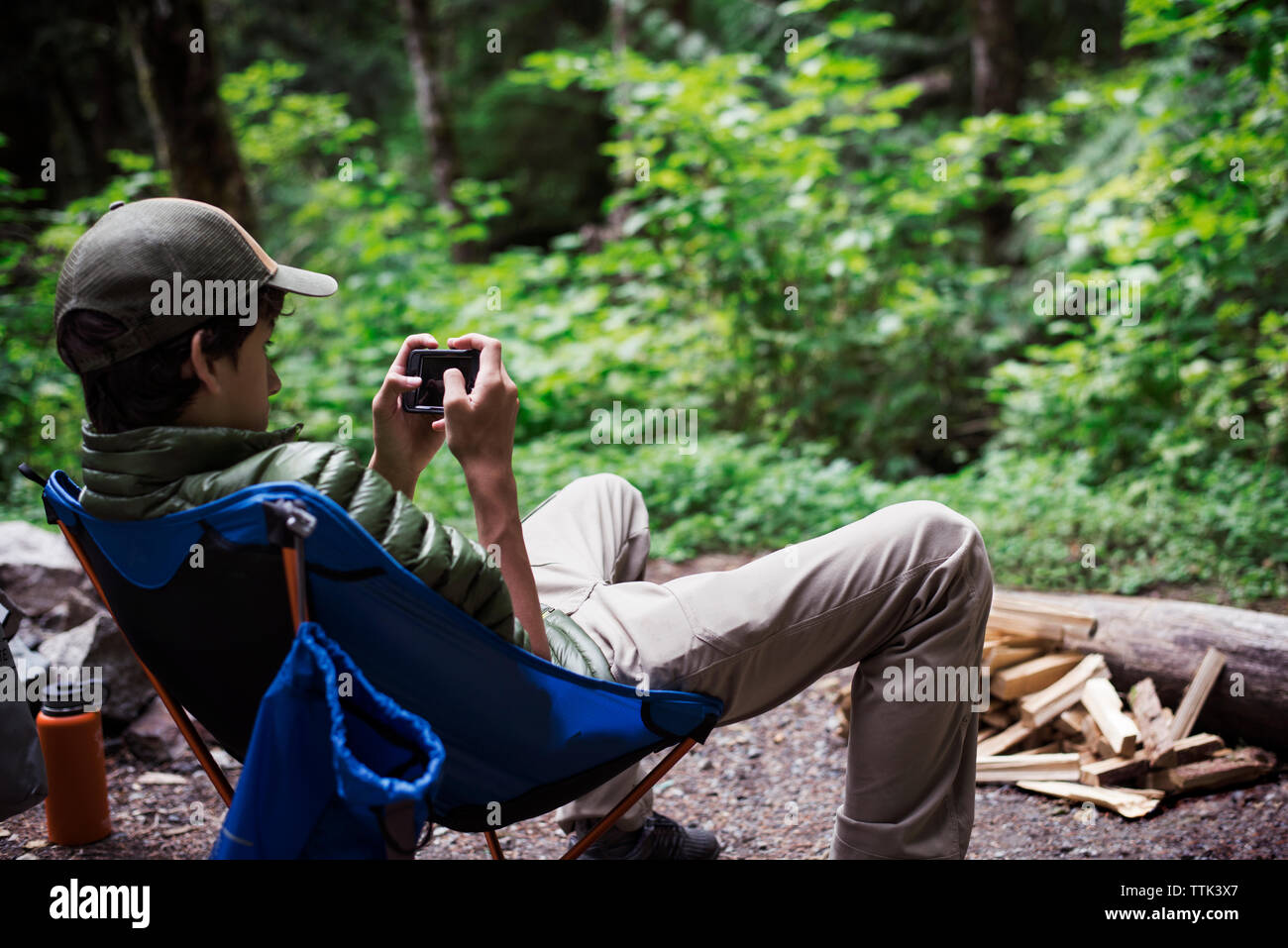 Hiker using smart phone while resting on chair at camp site Stock Photo ...