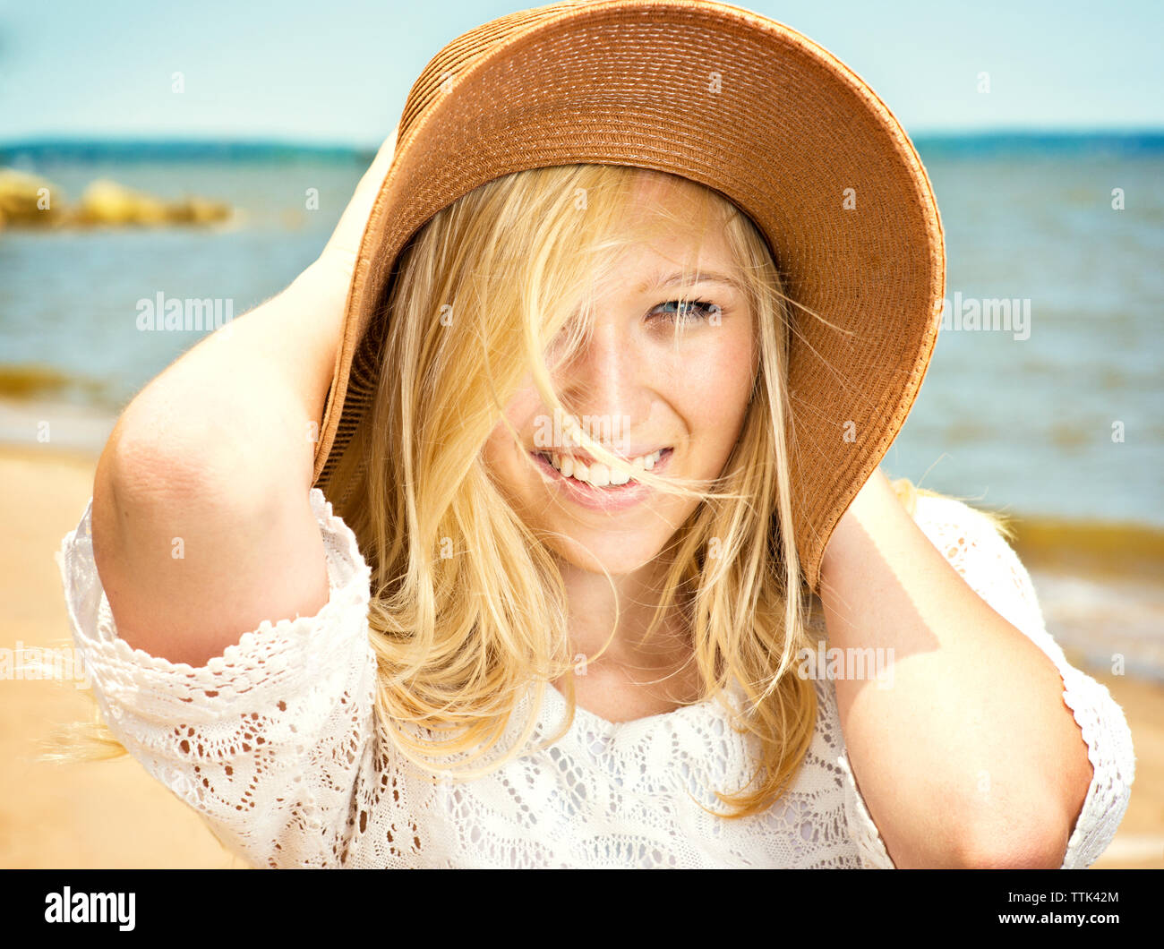 Portrait of smiling woman wearing sun hat at beach Stock Photo - Alamy