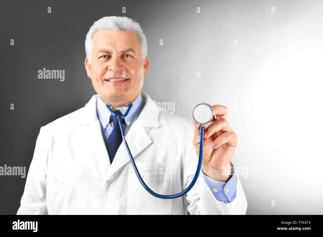 Professional doctor with stethoscope on grey background Stock Photo - Alamy