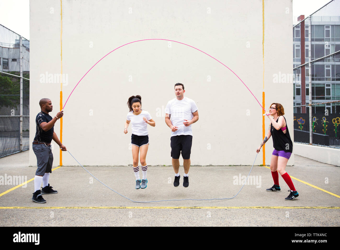 Friends playing double Dutch on street against wall Stock Photo - Alamy