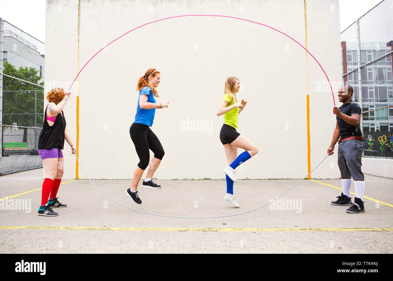 Friends enjoying double Dutch against white wall Stock Photo - Alamy