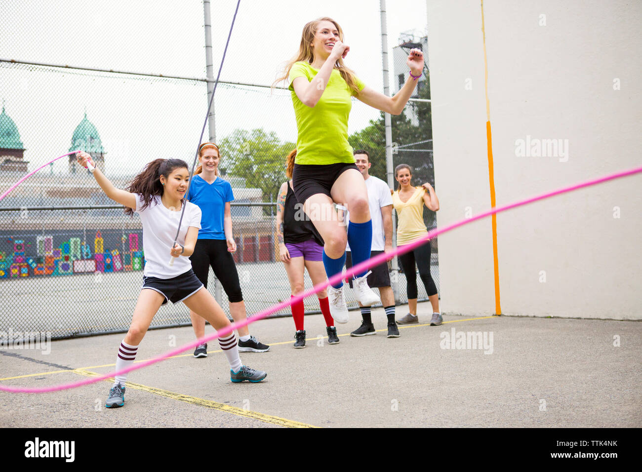 Friends performing double Dutch on street against fence Stock Photo - Alamy