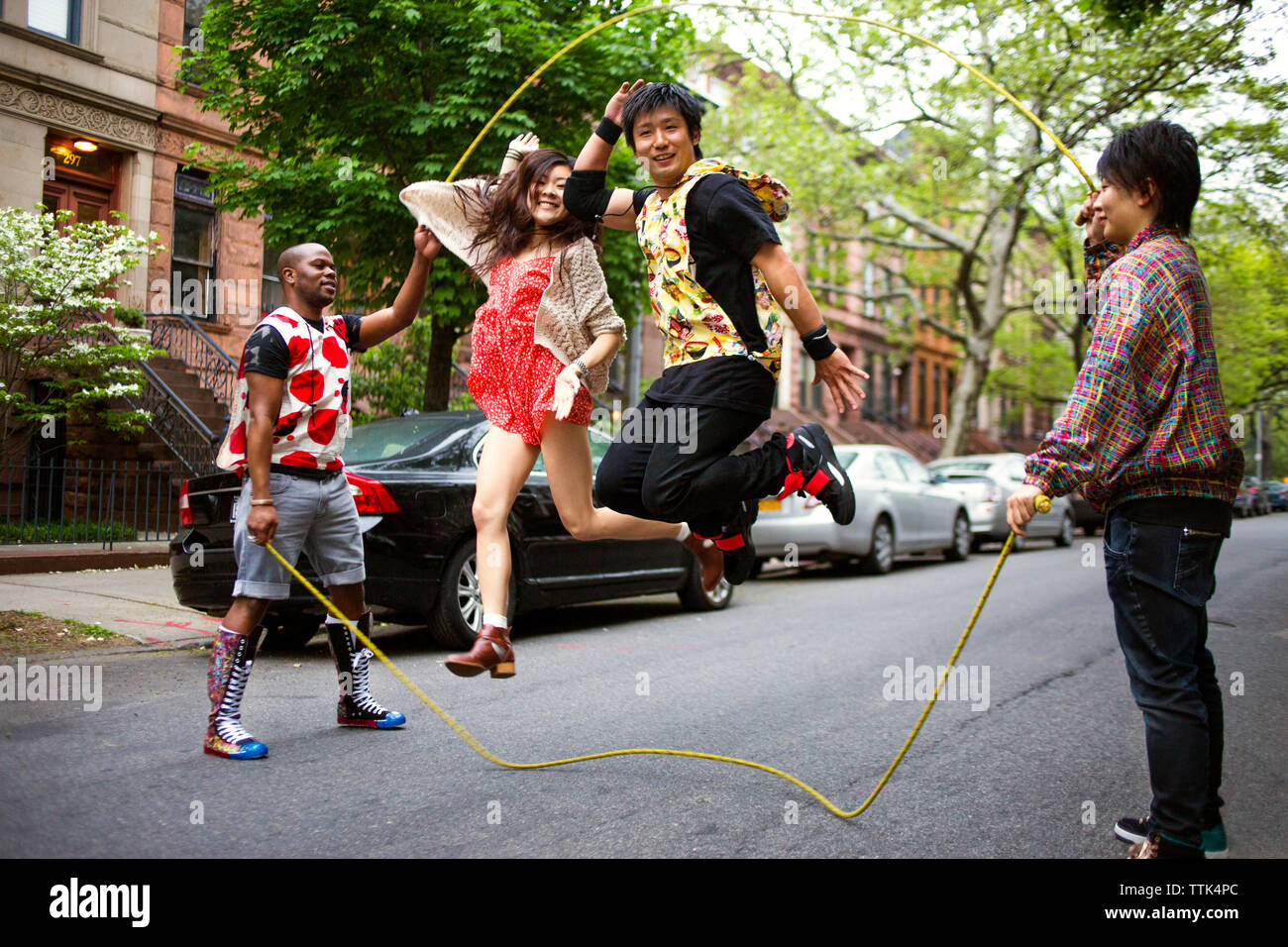 Friends enjoying double Dutch on street against parked cars Stock Photo ...